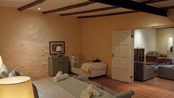 Quarto com cama, mesa de cabeceira, abajur e porta para outro cômodo.