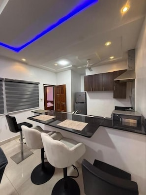 Cozinha moderna com ilha central, banquetas de bar e área de refeições.