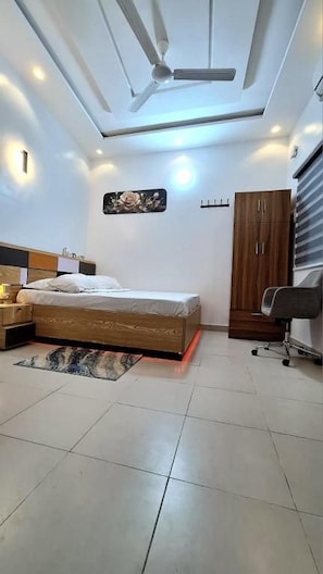 Quarto com cama, guarda-roupa, escrivaninha e ventoinha no teto.