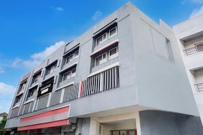Um edifício de vários andares com design arquitetônico moderno, apresentando varandas e uma placa visível indicando um serviço comercial.