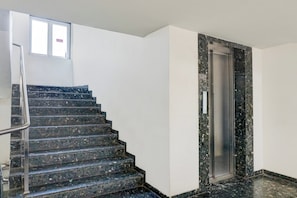 Uma escadaria com corrimão de metal que leva a uma porta com moldura metálica.
