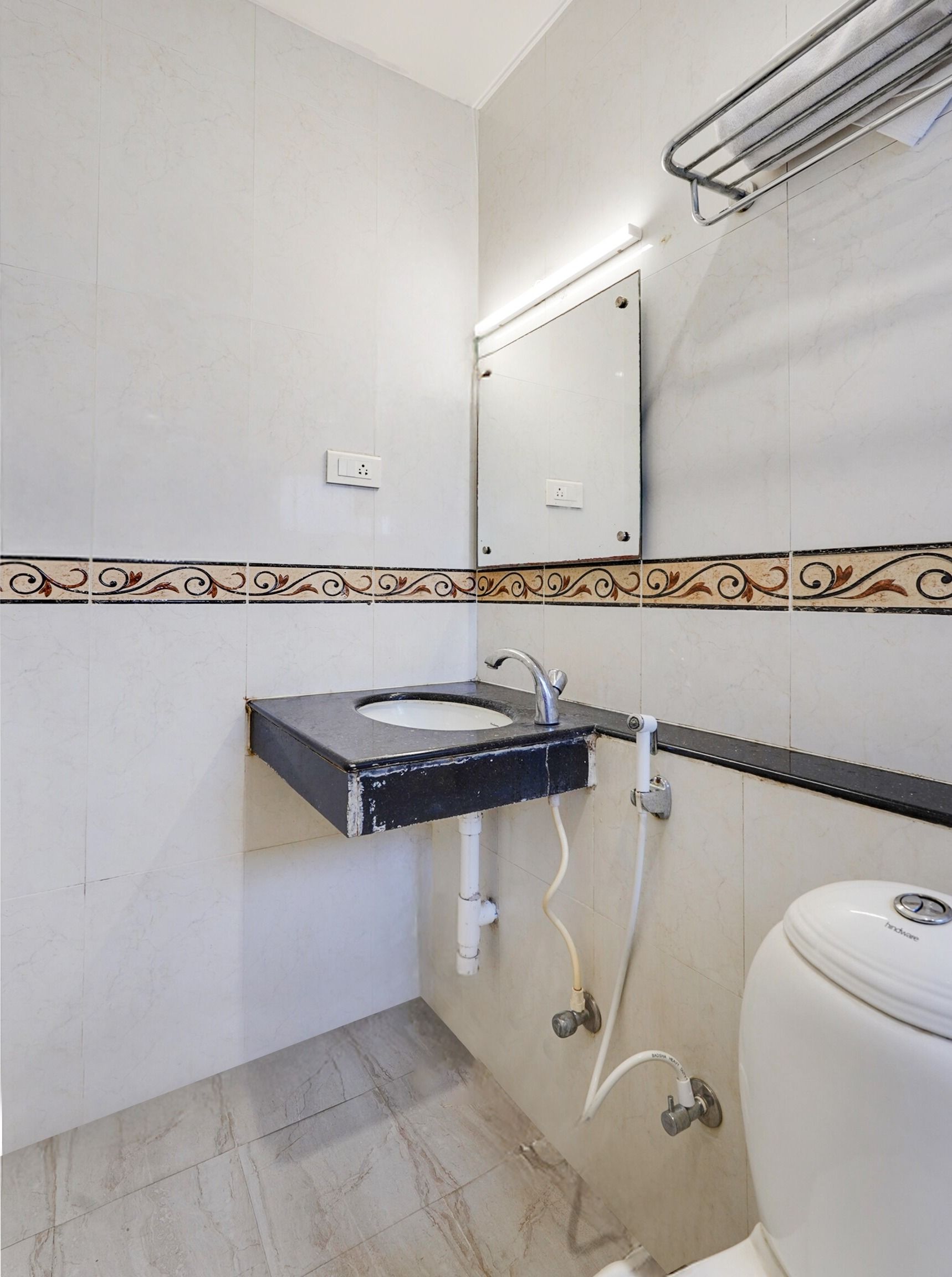 Casa de banho com sanita branca, lavatório com bancada preta e espelho sobre o lavatório.