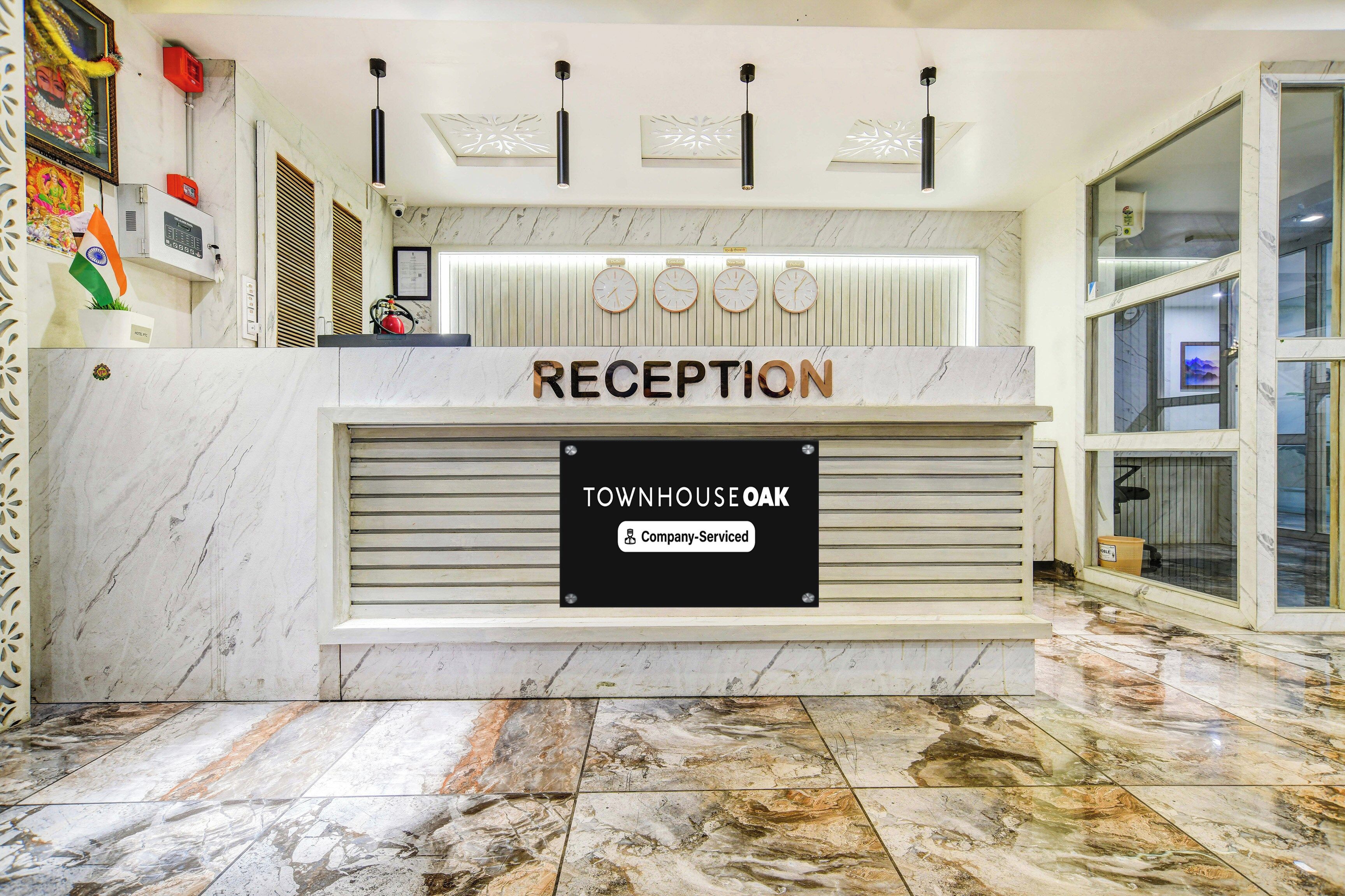 Bancada de recepção com superfície de mármore e placa indicando 'TOWNHOUSE OAK' e 'Serviços para Empresas'.
