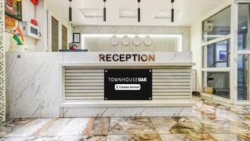 Bancada de recepção com superfície de mármore e placa indicando 'TOWNHOUSE OAK' e 'Serviços para Empresas'.
