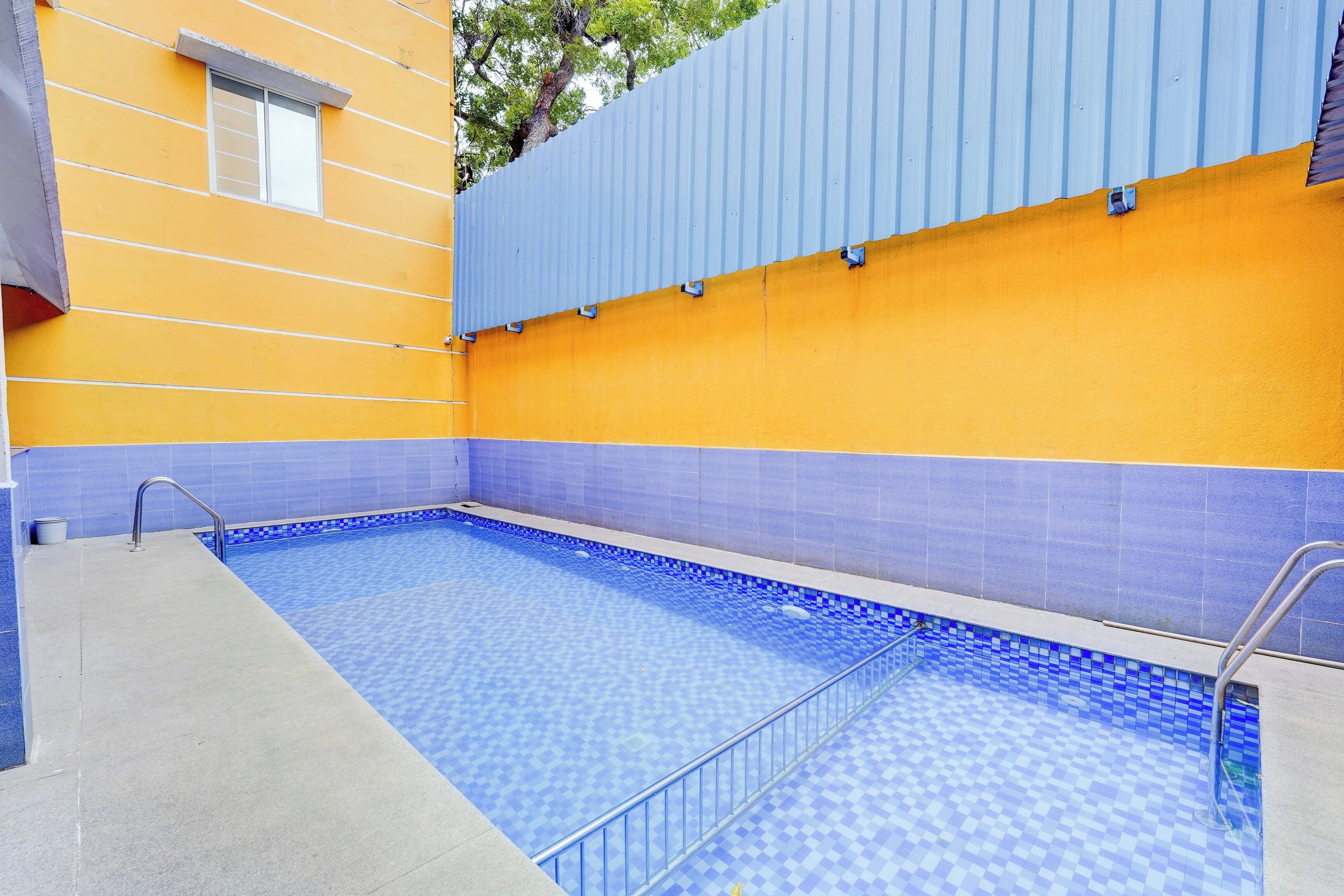 Uma piscina com piso em azulejos azuis e escada de metal.