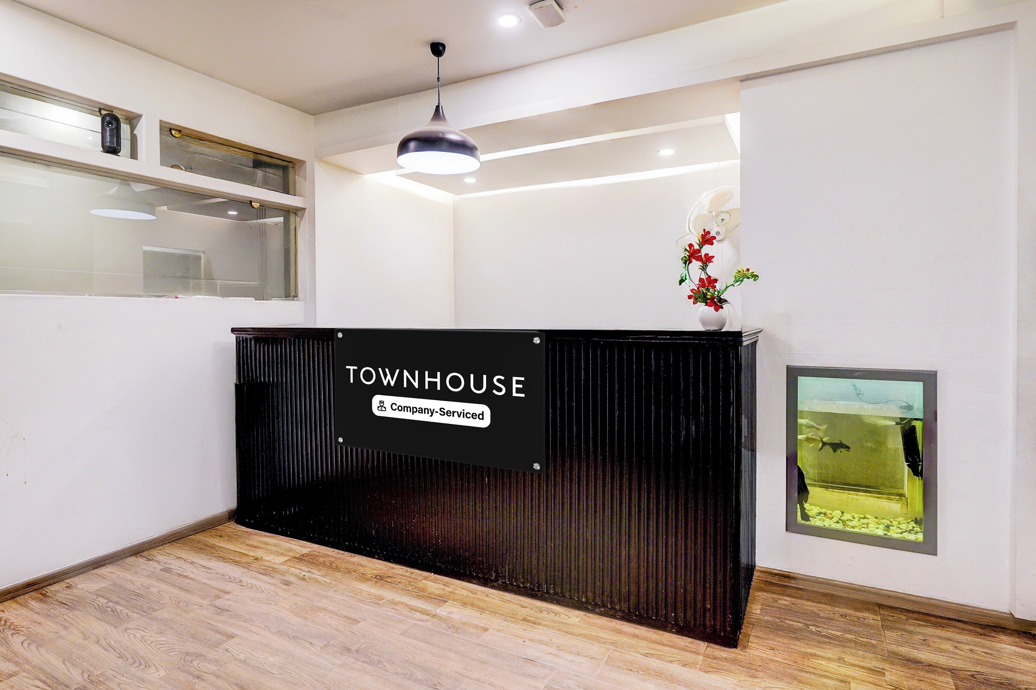 Uma receção com uma placa a indicar 'TOWNHOUSE Company Serviced' num interior moderno com soalho de madeira e um quadro emoldurado na parede.
