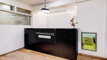 Uma receção com uma placa a indicar 'TOWNHOUSE Company Serviced' num interior moderno com soalho de madeira e um quadro emoldurado na parede.