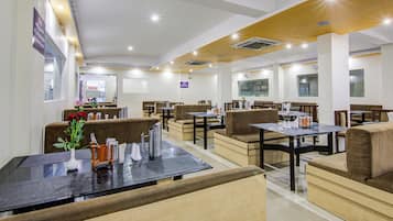 Um restaurante com cabines e mesas, algumas com assentos fixos.