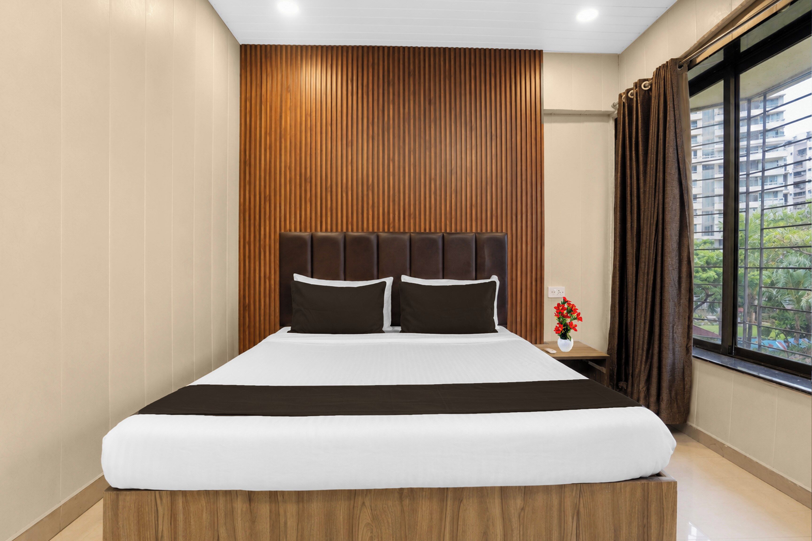 Quarto de hotel moderno com cama grande, parede de painéis de madeira e janela com cortinas.