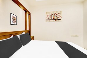 Quarto de hotel com uma cama grande, cabeceira de madeira, mesa de cabeceira e um quadro pendurado na parede.