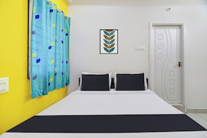 Quarto com cama, duas almofadas, porta e uma obra de arte na parede.
