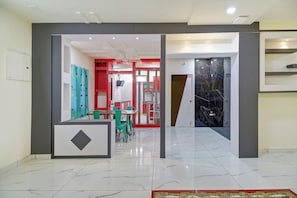 Um interior moderno com uma mesa de recepção, área de refeições com cadeiras e um corredor que leva a um quarto com parede de mármore preto.
