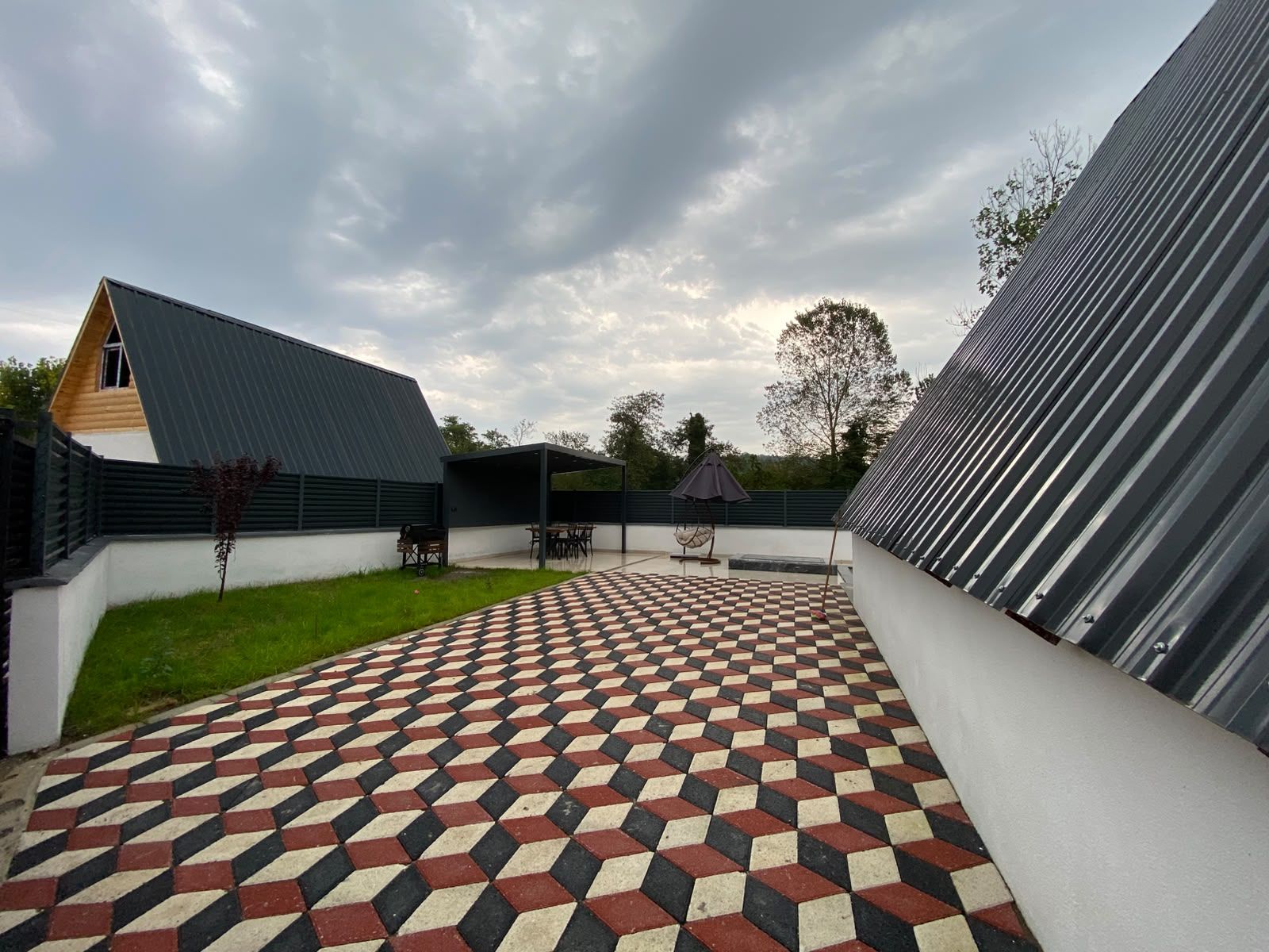 Uma área externa coberta com piso xadrez, churrasqueira e área de estar.