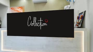 Balcão de recepção com uma grande placa preta com a palavra 'Collection' e uma parede branca com um quadro emoldurado.