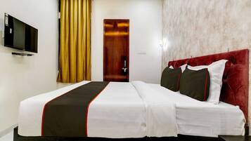 Quarto de hotel com uma cama, televisão, porta e cortina.