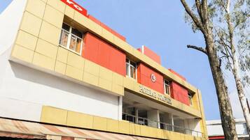 Um edifício de vários andares com uma fachada marcante em vermelho e amarelo, um letreiro com a inscrição 'PARALLEL COMPLEX' e uma varanda visível no andar térreo.
