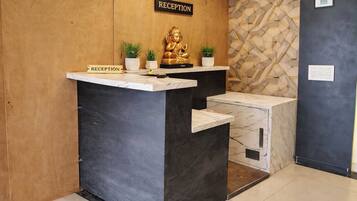Uma receção com uma placa, uma estátua de Buda e plantas.