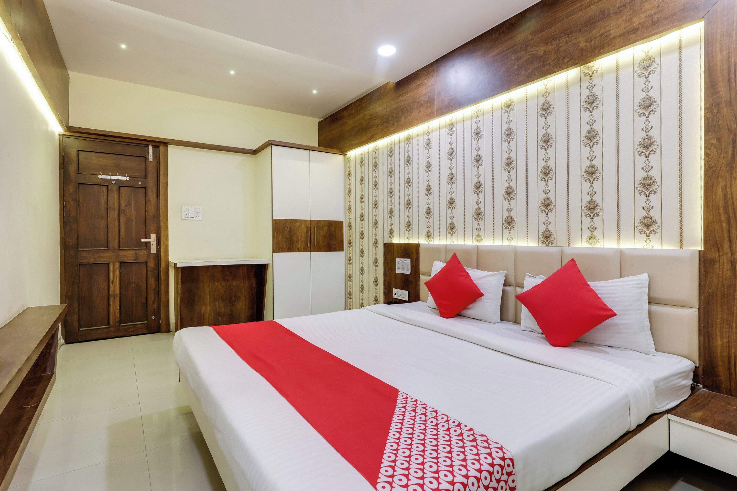 Quarto de hotel com uma cama grande, um guarda-roupa de madeira e uma parede com painéis decorativos.