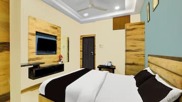 Quarto de hotel com cama, televisão na parede, mesinha com bandeja e ventoinha no teto.