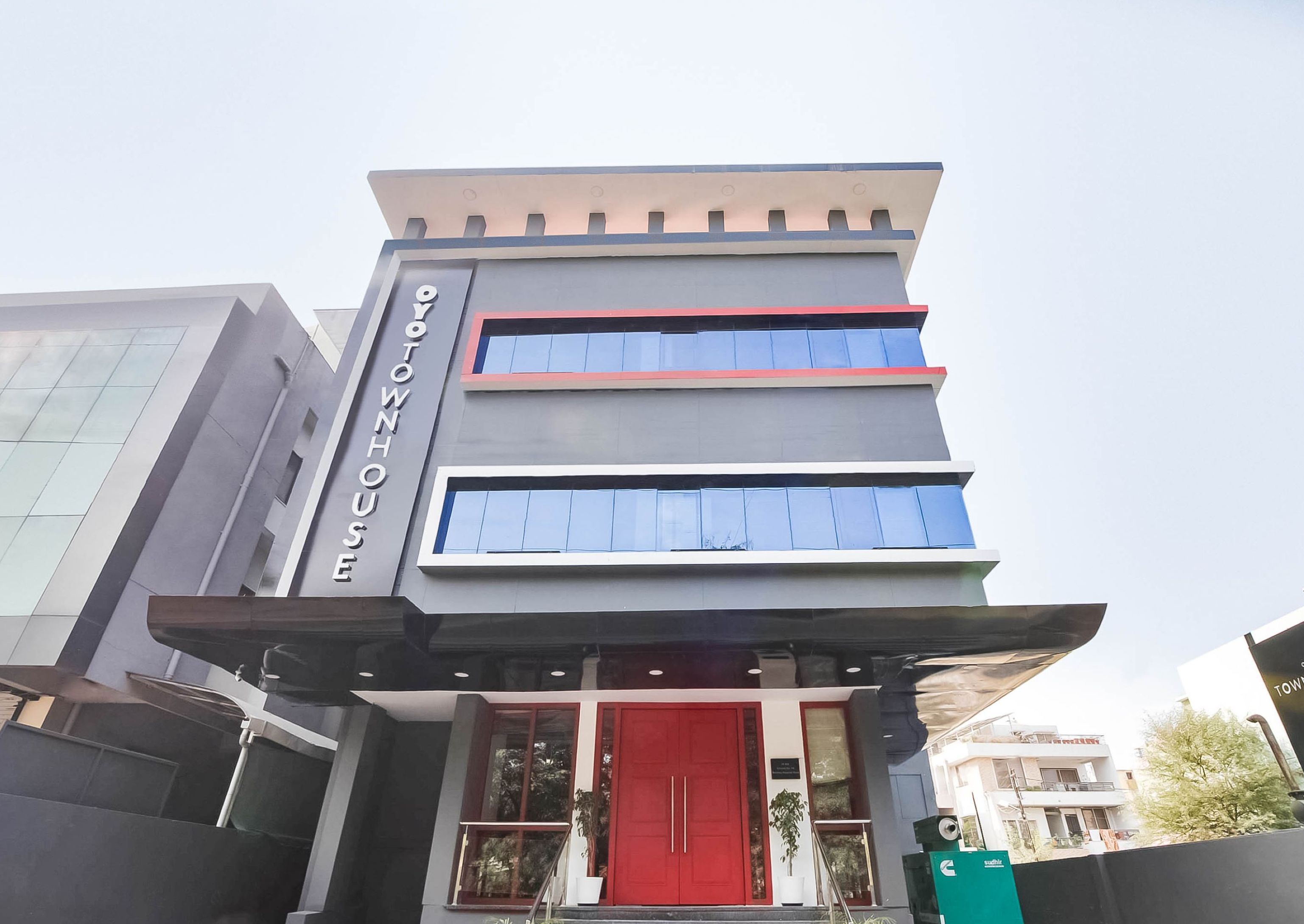 Um edifício de vários andares com uma porta vermelha destacada e uma placa que diz 'TOWNHOUSE'.