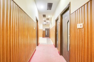 Um corredor com painéis de madeira nas paredes, carpete vermelho e portas com números de quarto.