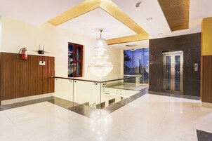 Um hall moderno com guarda-corpo de vidro, um candelabro e um elevador.