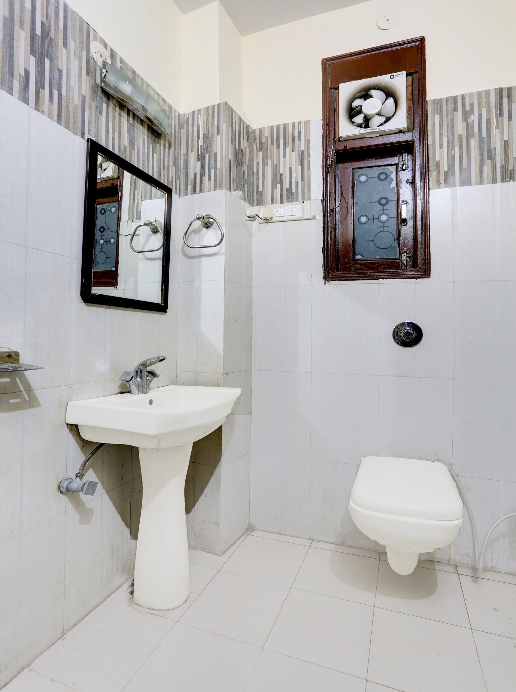 Casa de banho com lavatório assentado, sanita, espelho e porta-toalhas.
