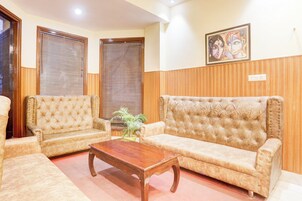 Um quarto com dois sofás bege, uma mesa de centro de madeira e um vaso com planta.