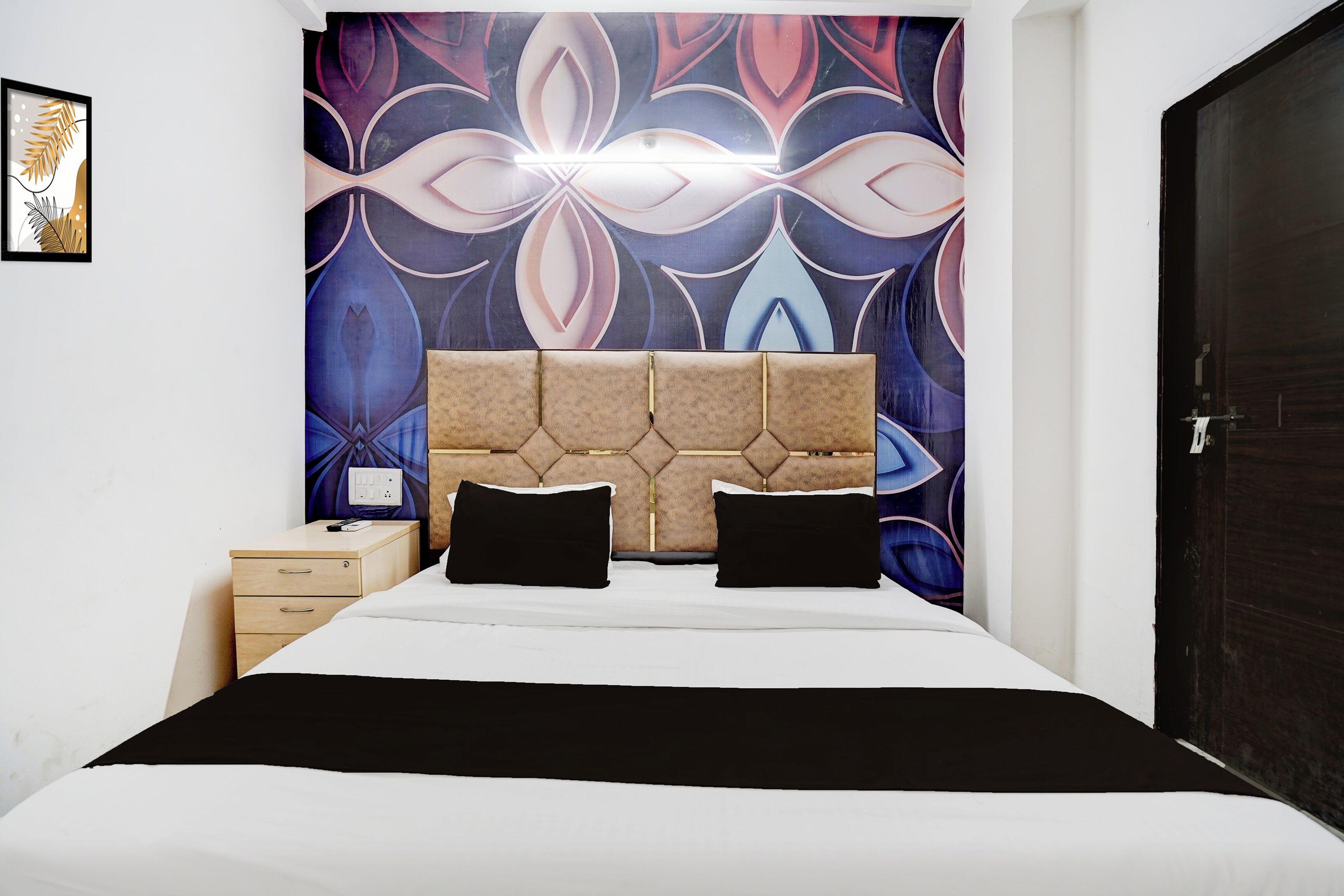 Quarto de hotel com cama, cabeceira, mesa de cabeceira e porta.