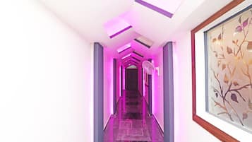 Um corredor com design moderno, apresentando uma escada, um ventilador e uma obra de arte emoldurada na parede.