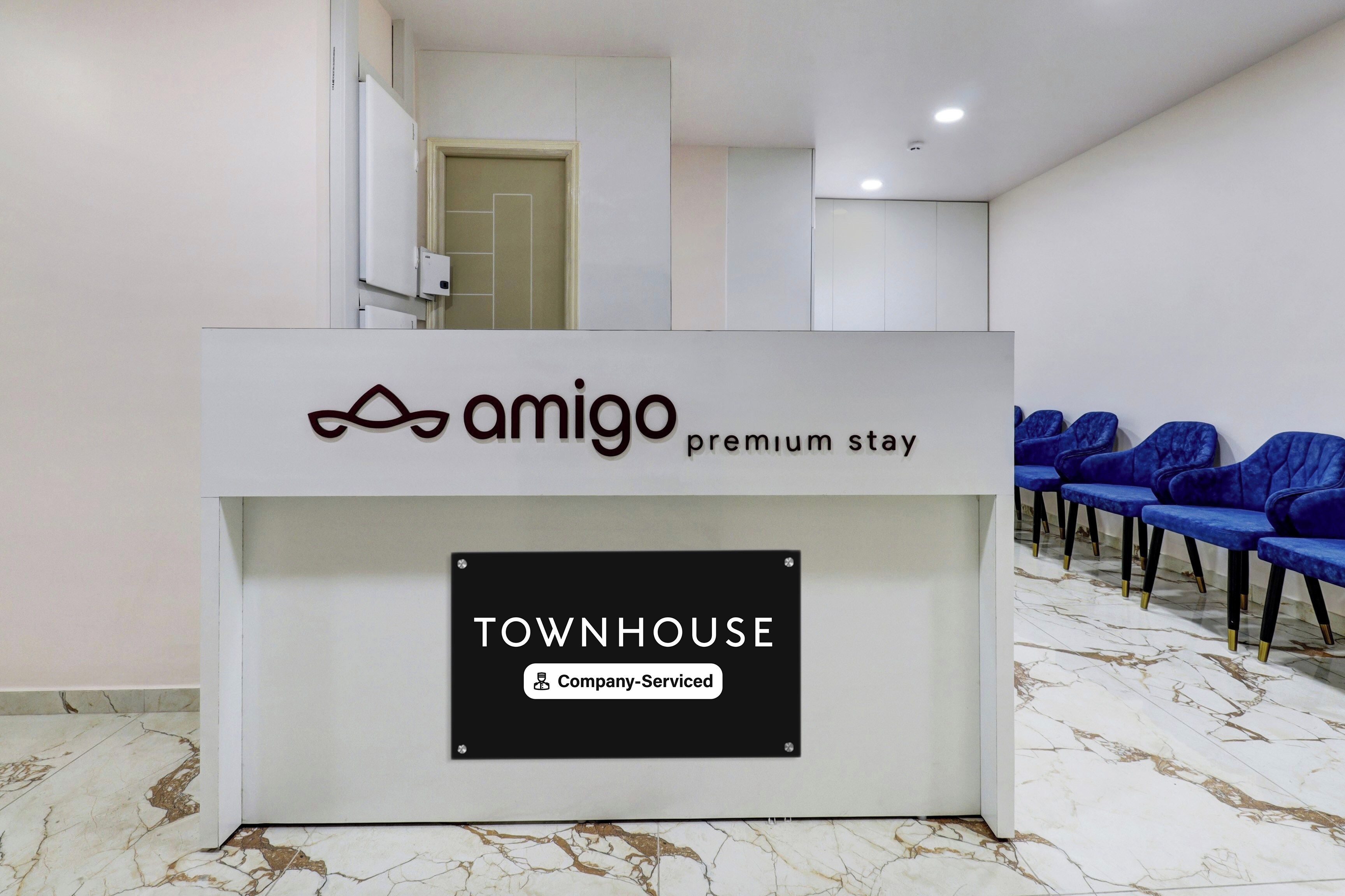 Uma mesa de recepção com uma placa indicando 'amigo premium stay' e a inscrição 'TOWNHOUSE Company-Serviced'.