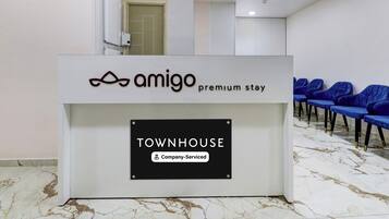 Uma mesa de recepção com uma placa indicando 'amigo premium stay' e a inscrição 'TOWNHOUSE Company-Serviced'.