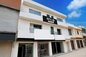 Um hotel moderno com uma placa chamativa, janelas grandes e fachada plana.