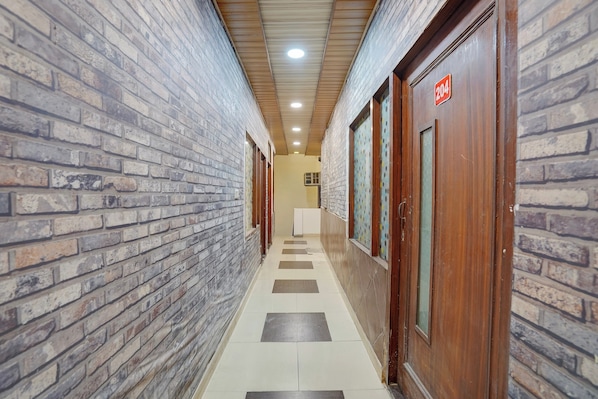 Um corredor com paredes de tijolo, portas de madeira e chão de azulejos.