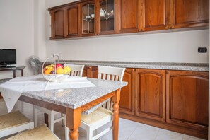Cozinha com armários de madeira, bancada de granito e mesa de jantar com cadeiras.