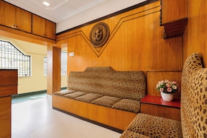 Uma área de recepção com balcão de madeira, um sofá com almofada estampada de leopardo e um emblema decorativo na parede.