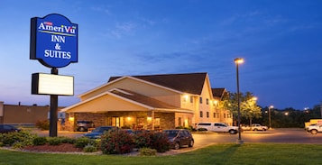 Um hotel com a placa AmeriViu Inn & Suites, um estacionamento e fachada bem iluminada.