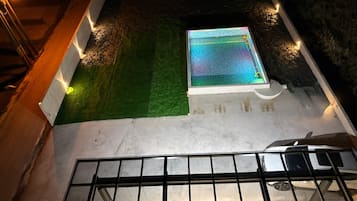 Terraço no telhado com área de grama sintética verde, estrutura de vidro e guarda-corpo de metal.