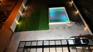 Terraço no telhado com área de grama sintética verde, estrutura de vidro e guarda-corpo de metal.