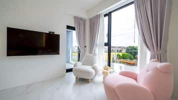 Uma sala de estar moderna com televisão de tela plana na parede, uma poltrona confortável e um sofá.