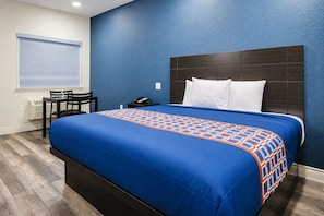 Quarto de hotel com cama, escrivaninha e cadeira.