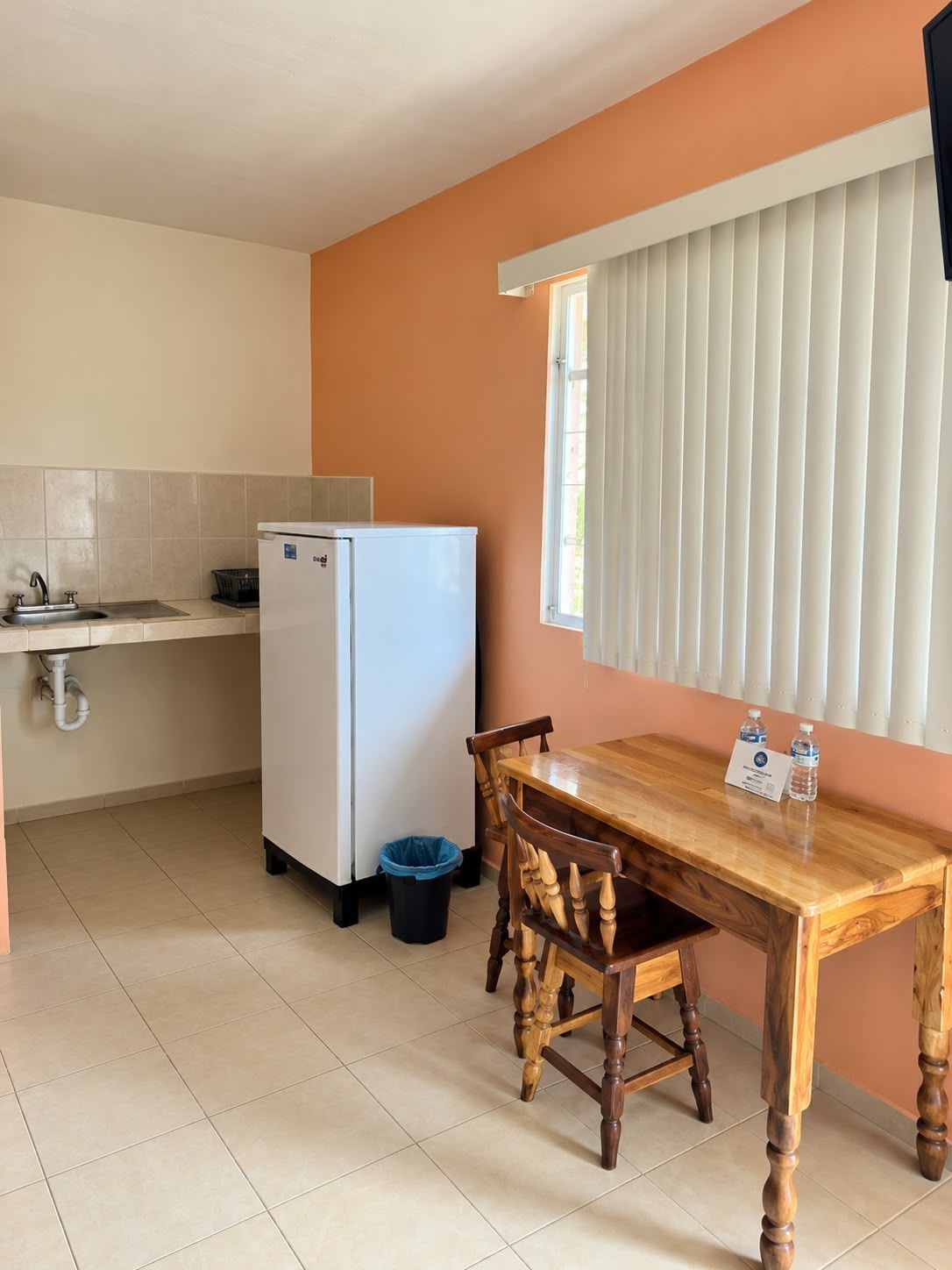 Cozinha compacta com geladeira, pia e mesa de jantar com cadeiras.