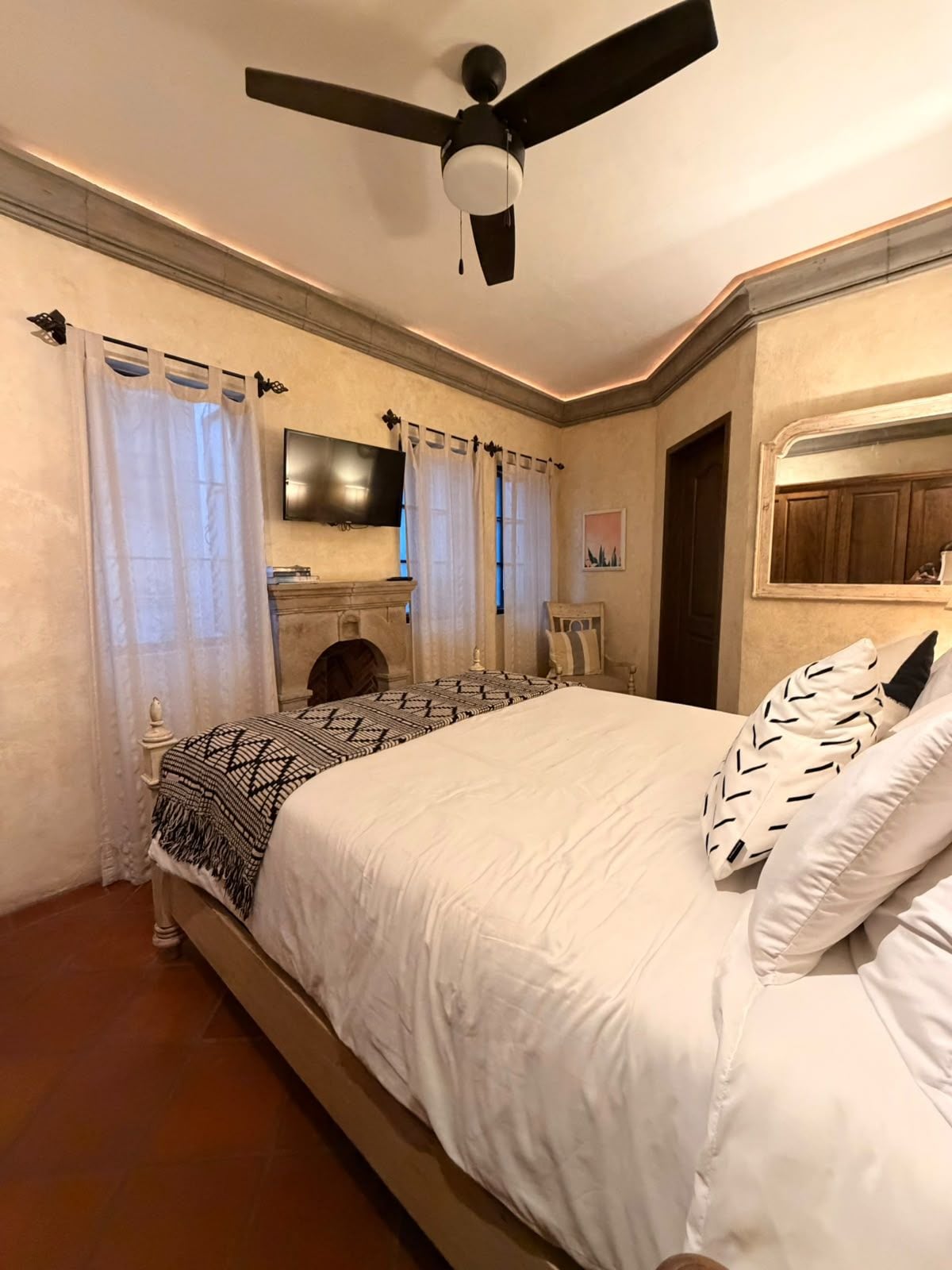 Quarto com cama, ventilador de teto, televisão e lareira.