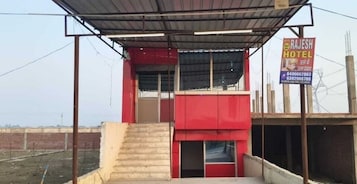 Edifício vermelho com placa indicando Rajesh Hotel, uma escadaria e vista da área circundante.