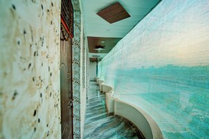 Um corredor com piso estampado, uma escadaria e uma parede com superfície texturizada.