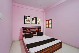 Quarto com uma cama, uma janela e três quadros na parede.