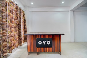 Balcão de recepção com uma placa indicando 'OYO', em um interior moderno com paredes lisas e cortina estampada.