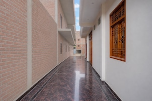 Um corredor com paredes de tijolo, piso lustroso e porta de madeira com janela.