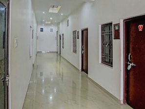 Corredor com portas, piso ladrilhado e iluminação embutida.