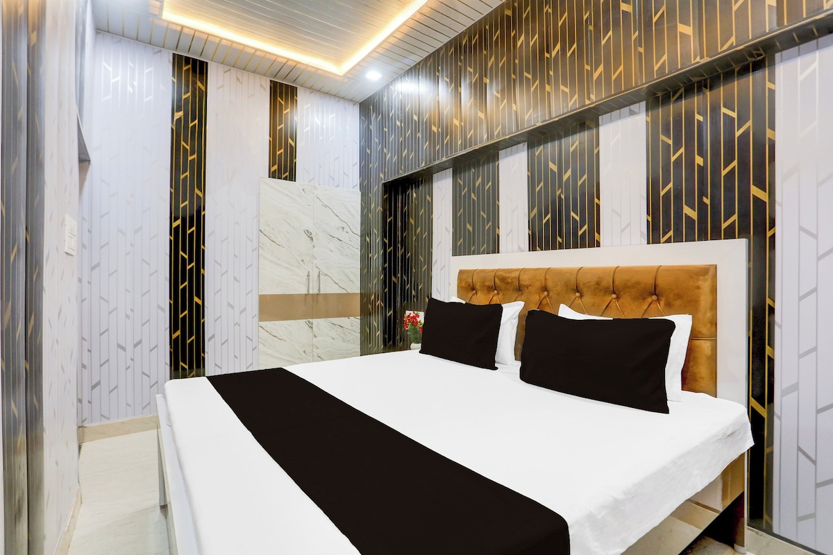 Quarto de hotel com uma cama grande, cabeceira e paredes estampadas.